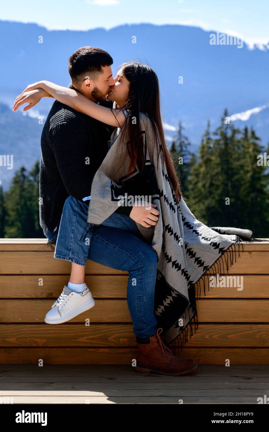 Loving couple wrapped in a blanket sitting on the veranda of a mountain ...