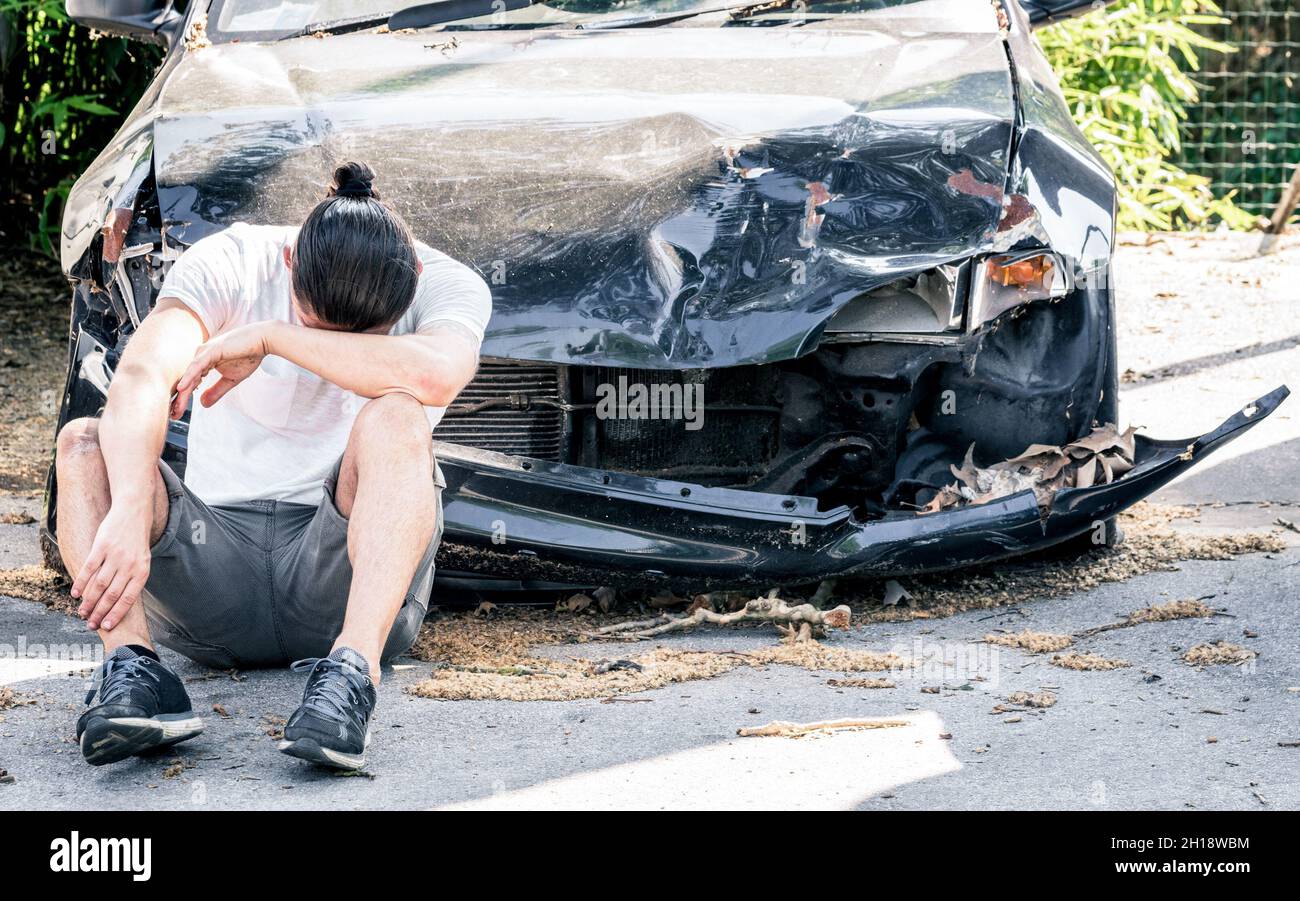 Desperate man crying on his old damaged car after a crash accident ...