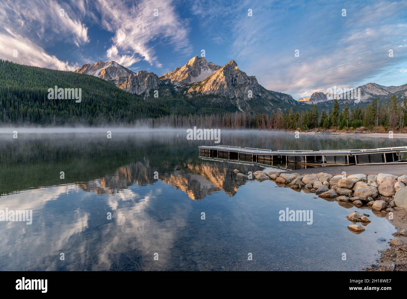 Boat dock extends into a lake reflection Stock Photo - Alamy