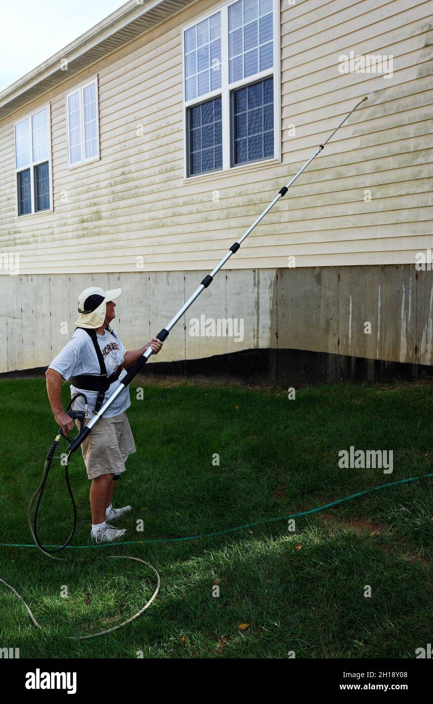 man power washing house, long wand, removing mildew, part clean ...
