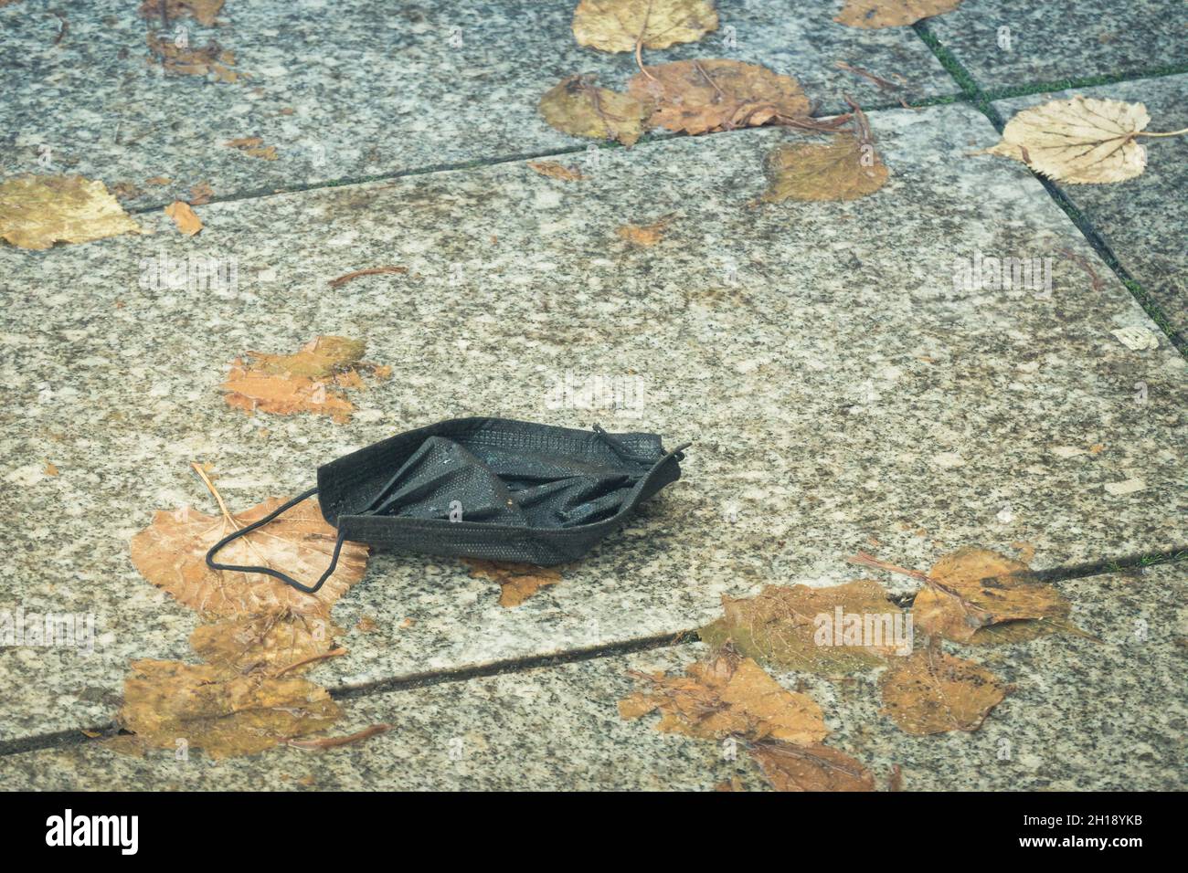 Old used disposable face mask dropped on sidewalk in the city Stock ...