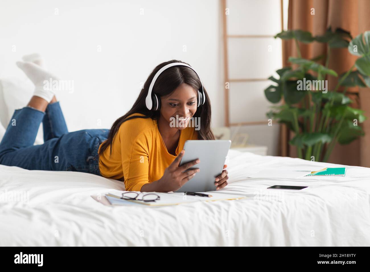 African American Female Student Using Tablet Wearing Headphones At Home ...