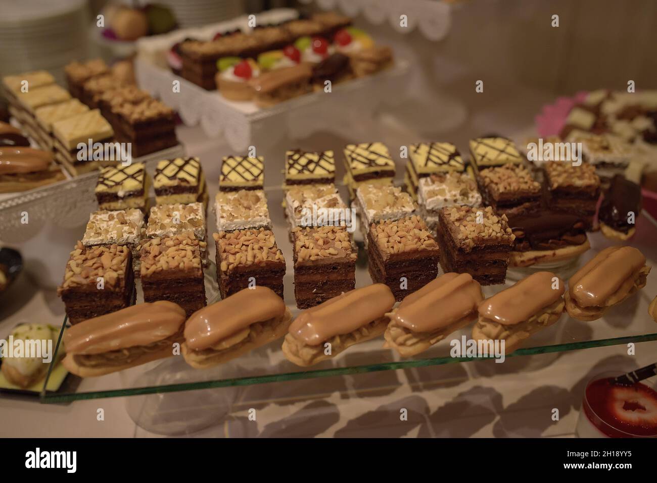 Assortment of small sweet treats, bite-sized eclairs with coffee ...