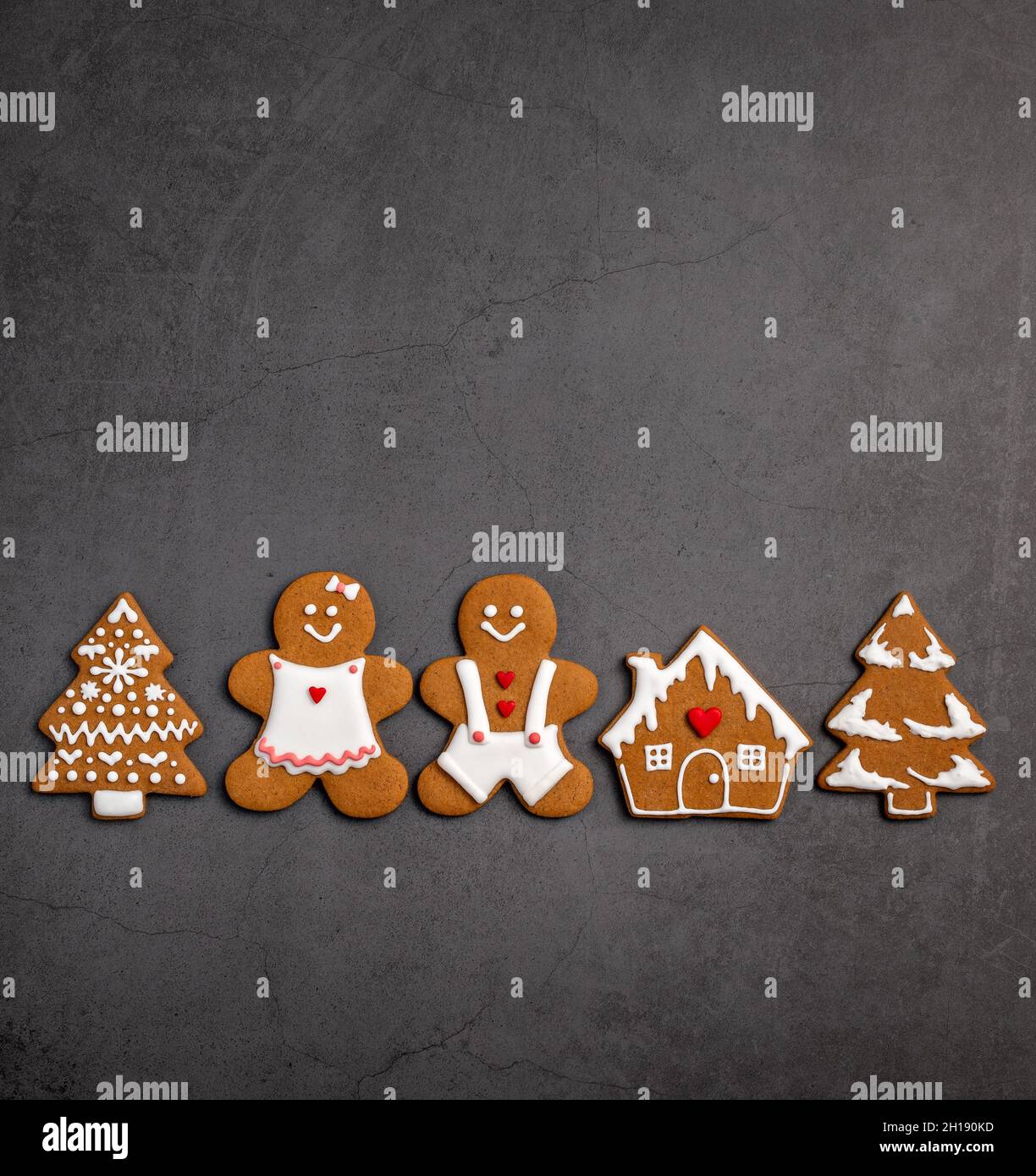 Christmas gingerbread cookies. Man woman and house in a row on a grey ...