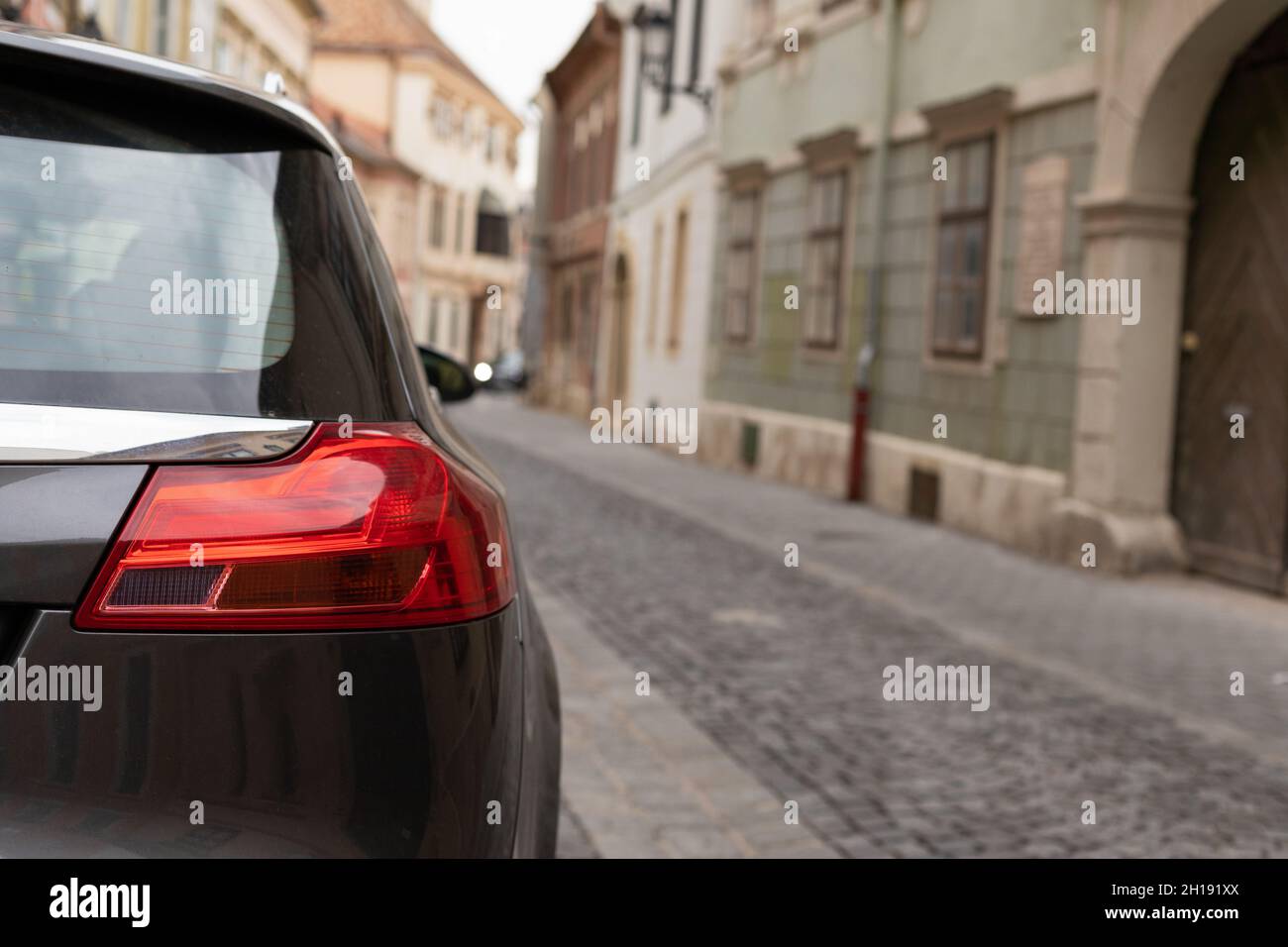 Scenic picture of a street in Sopron medieval center, cars parked along ...