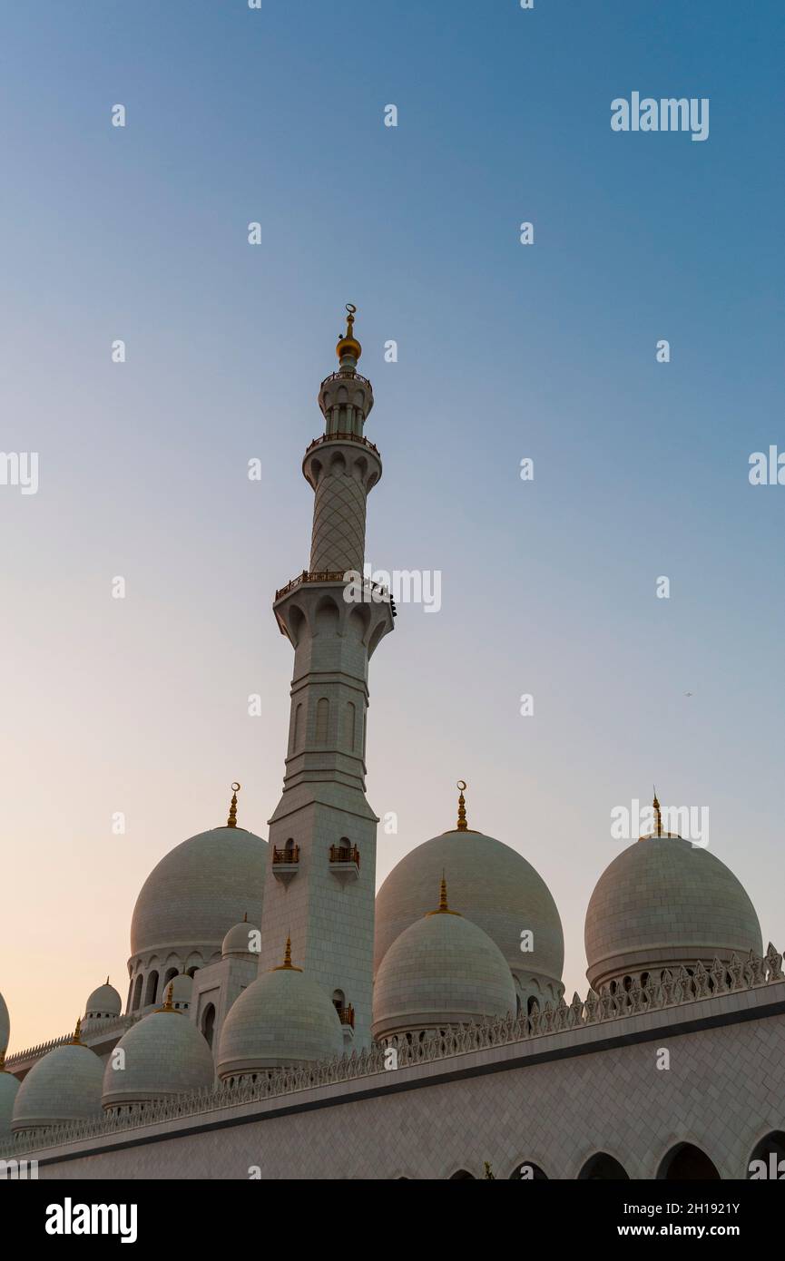 The domes and minaret of the Sheikh Zayed Grand Mosque at sunset ...