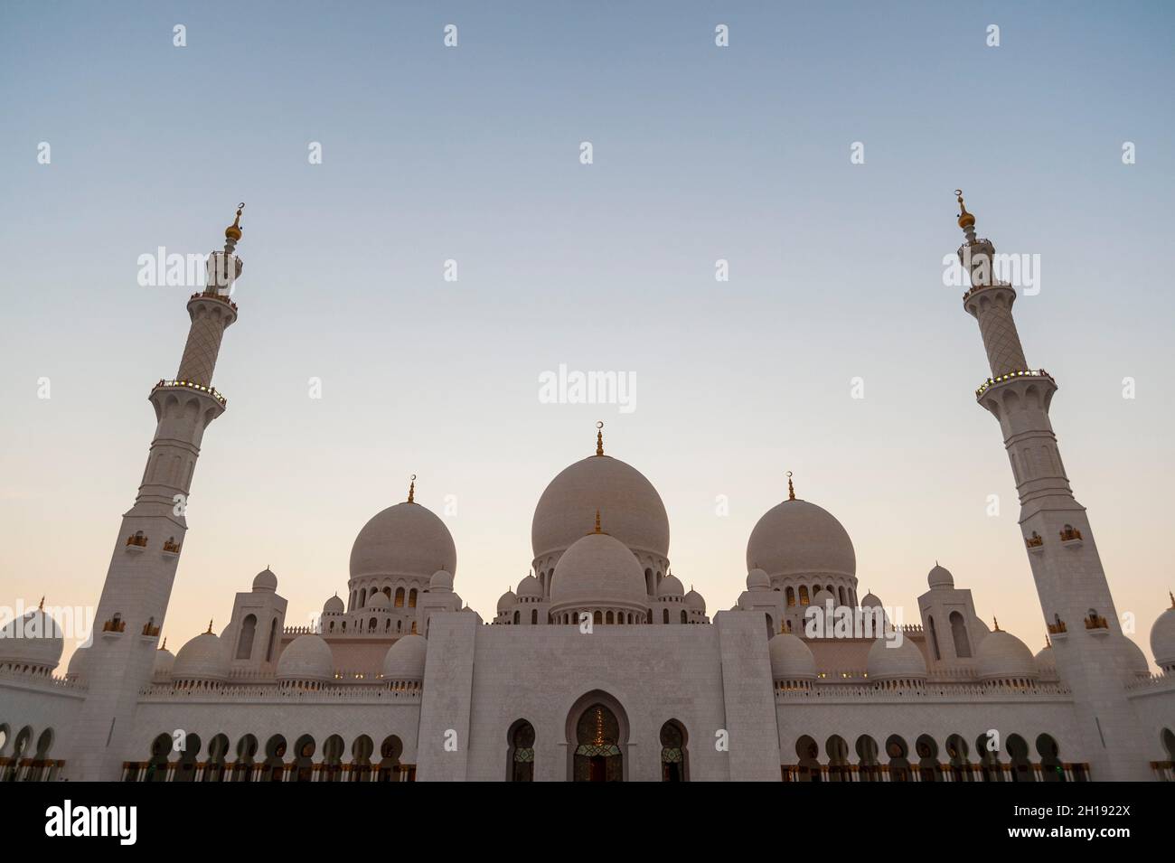 A view of minarets and domes at the Sheikh Zayed Grand Mosque at sunset ...