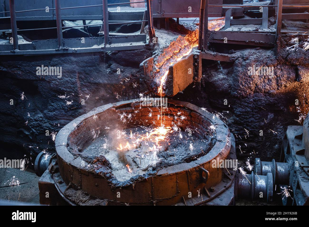 Molten iron flow. Liquid metal is poured into the ladle in a thin ...
