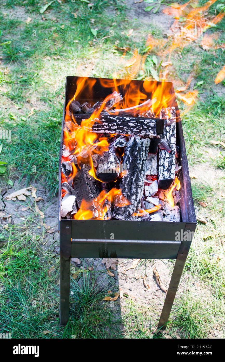A vertical shot of a barbeque stand with burning wood inside Stock ...