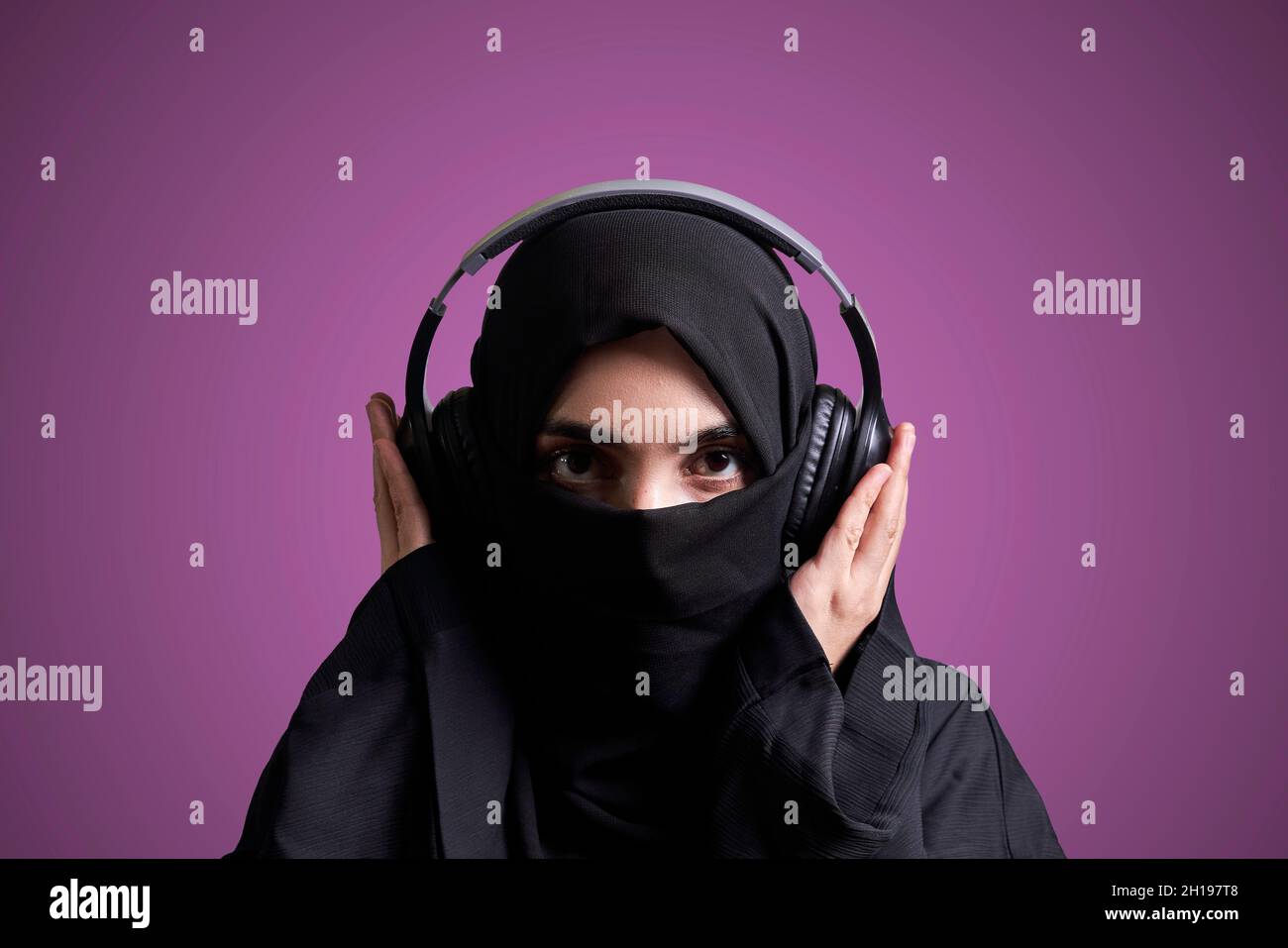 Muslim woman in hijab listening to music with wireless headset. Arabic ...