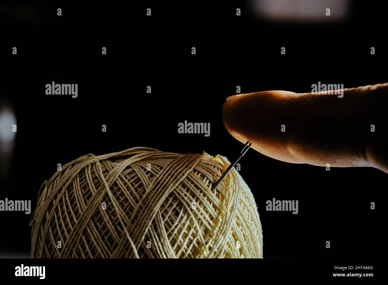 A finger pressing on the needle attached in the yellow thread bundle ...