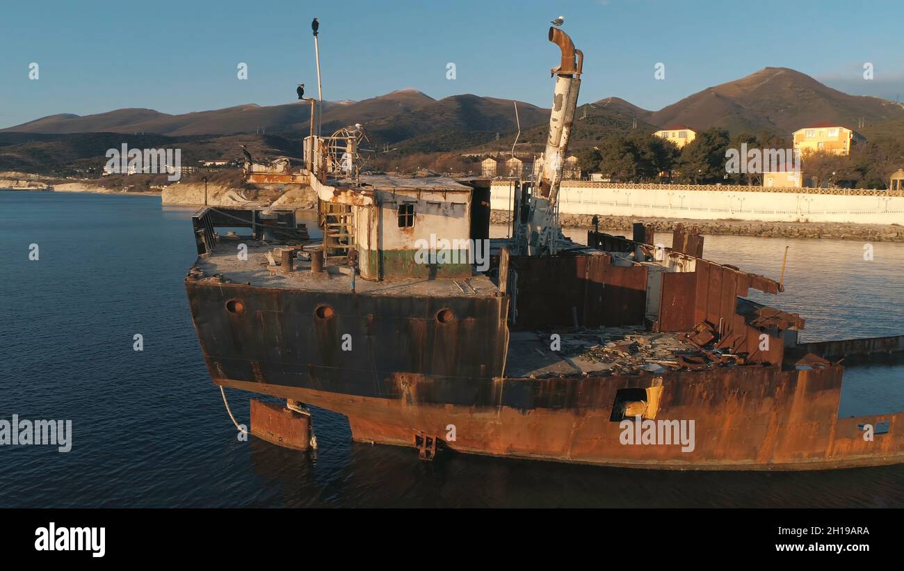Close-up of old and rusty sunken ship on a shoal against the coastline ...