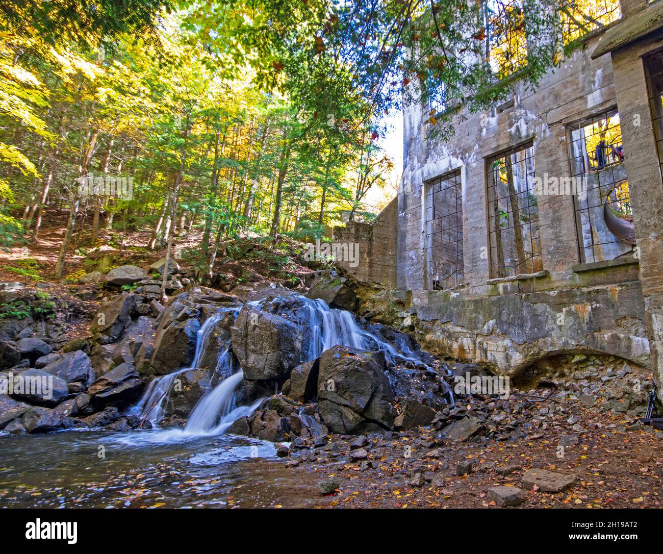 Waterfall in autumn beside the ruins of an old laboratory in the woods ...