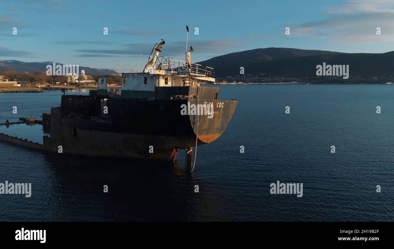 Close-up of old and rusty sunken ship on a shoal against the coastline ...