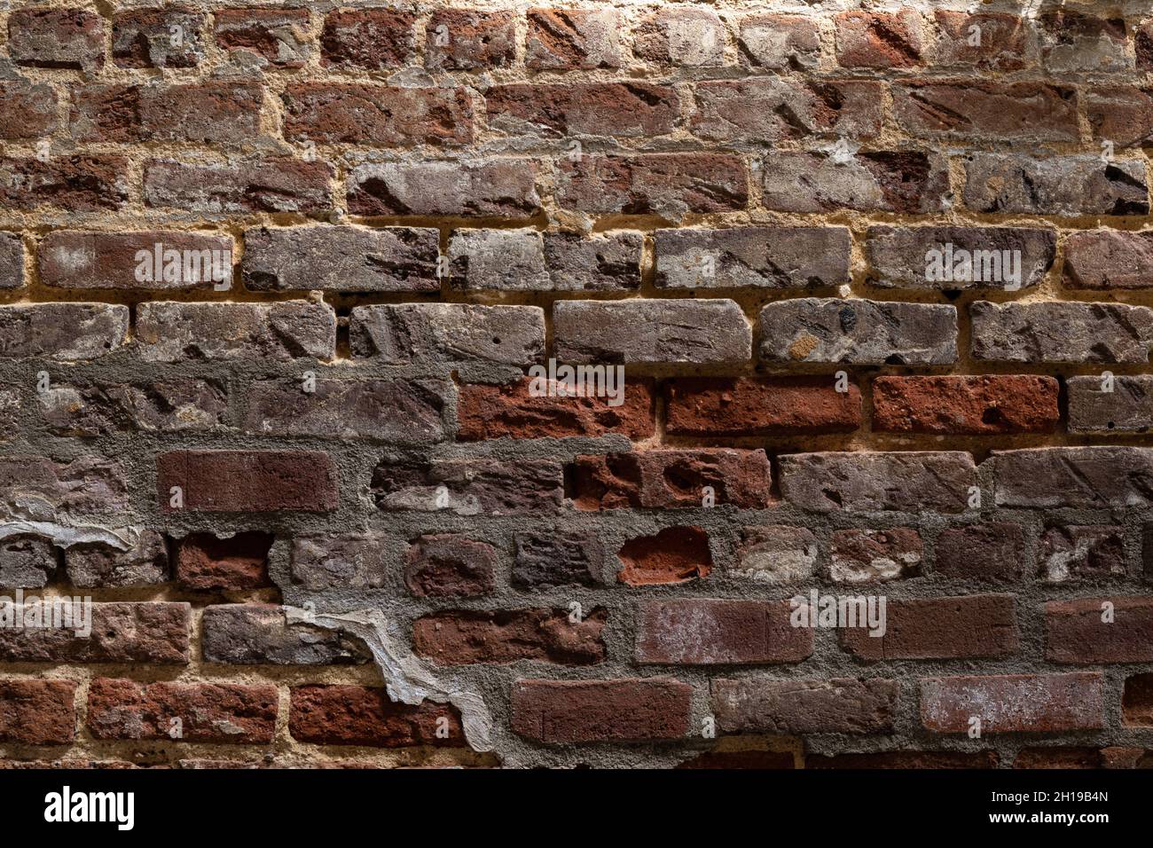 Red brick wall with numerous levels of decay and repair, horizontal ...