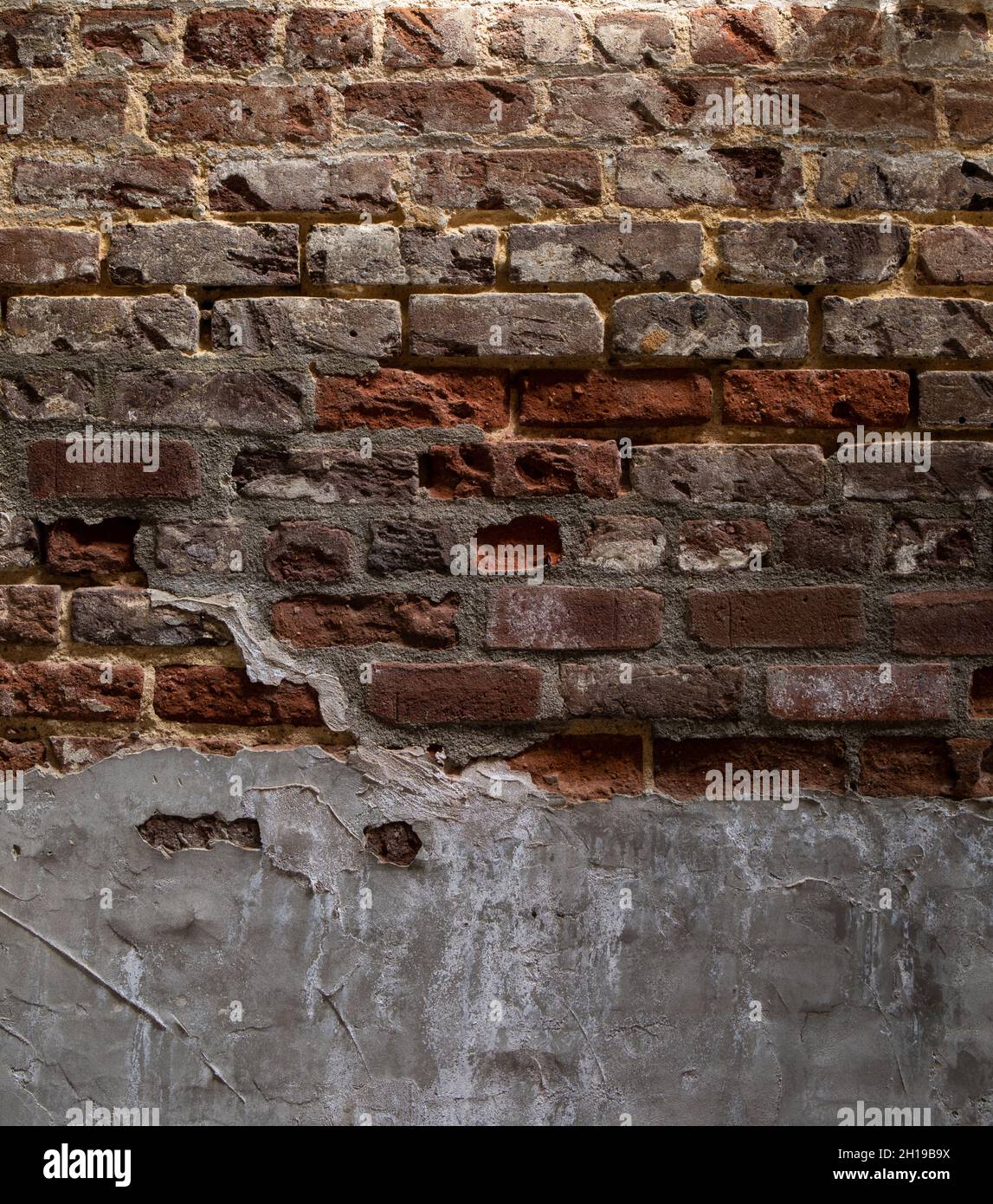 Weathered and decaying brick wall with multiple layers of concrete and ...
