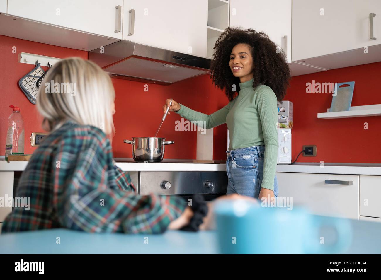 Two young multiracial students girls cooking in the youth hostel ...