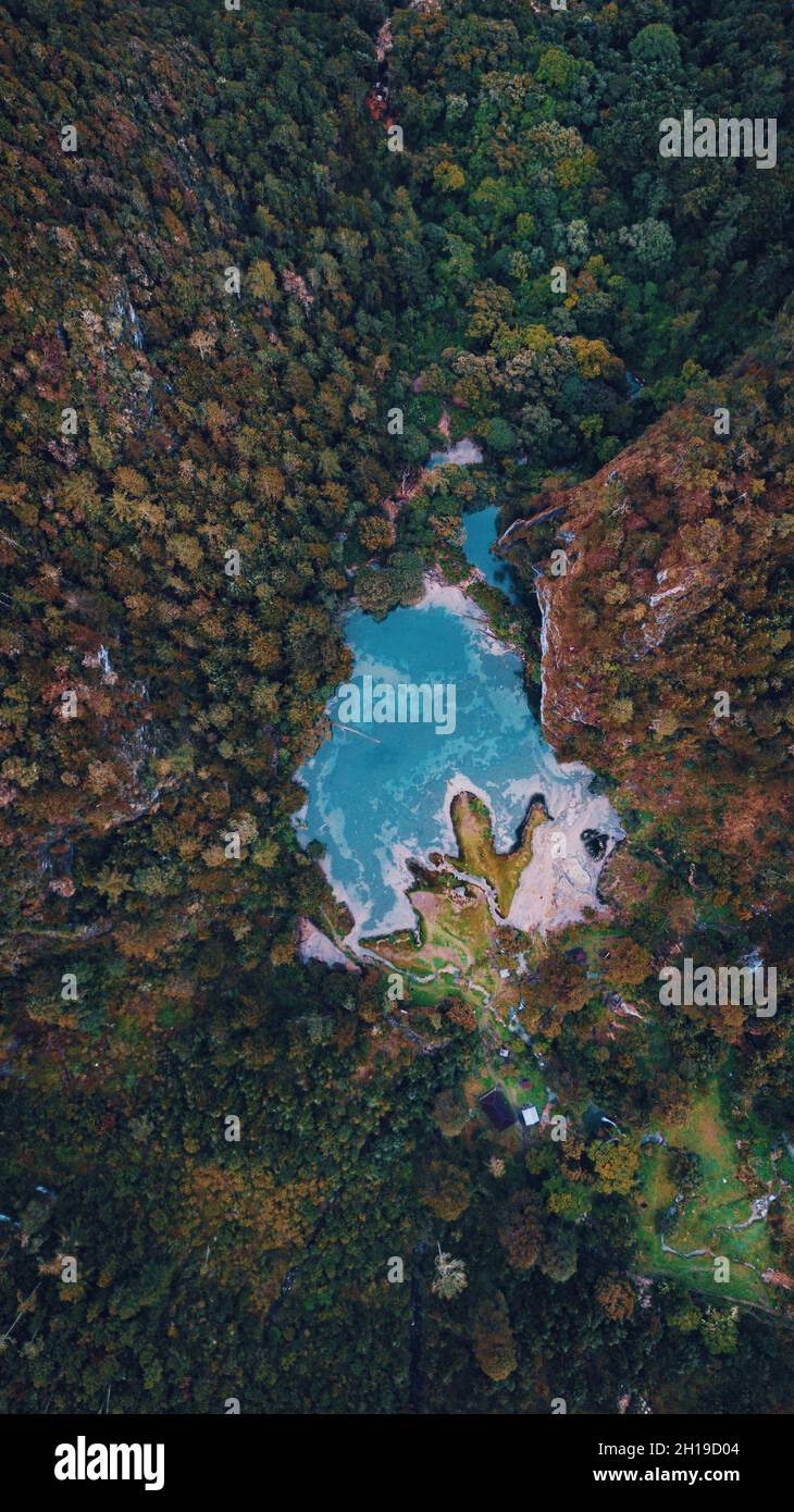 An aerial view of a small lake in the forest with autumn colors trees ...