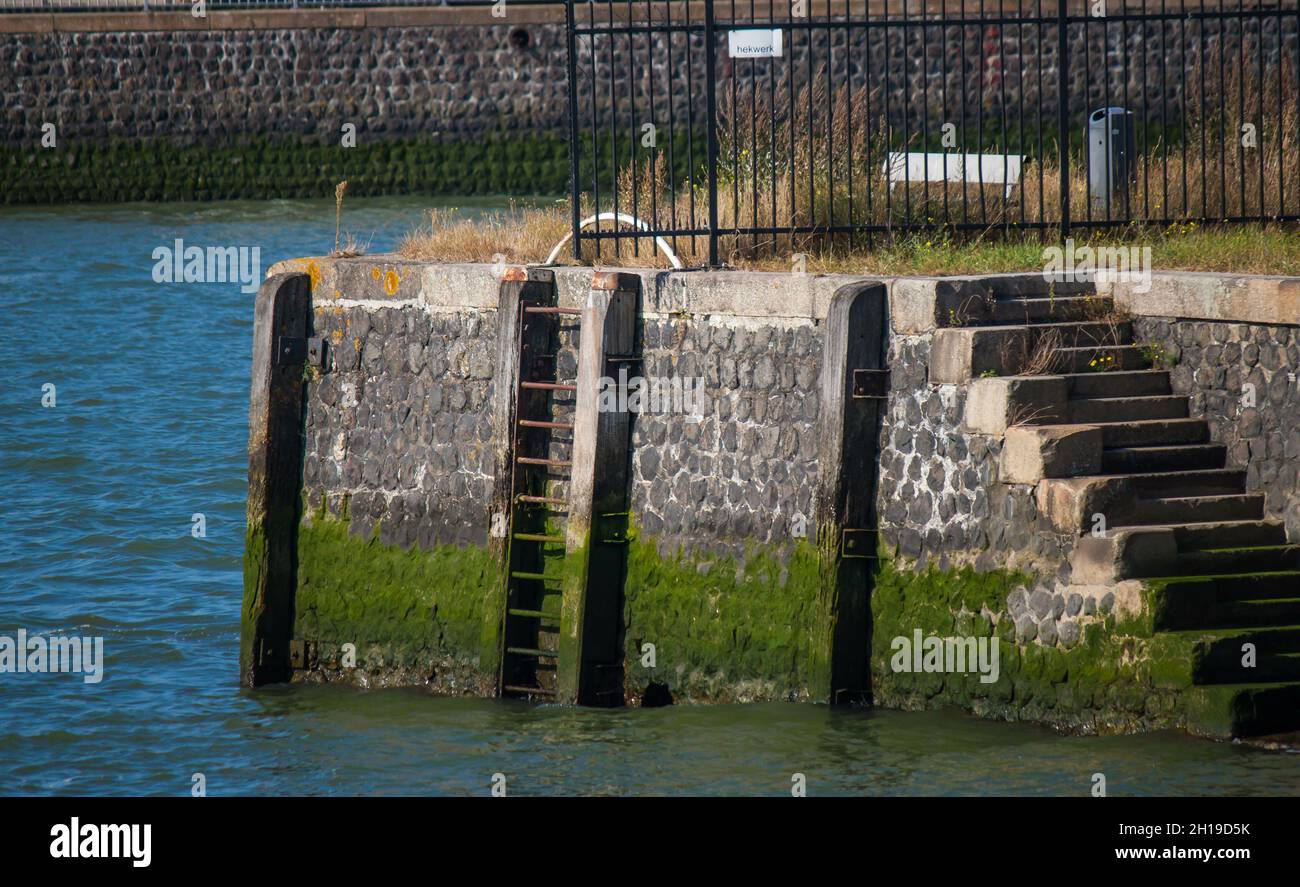 A stone pier with a ladder down to the lake Stock Photo - Alamy