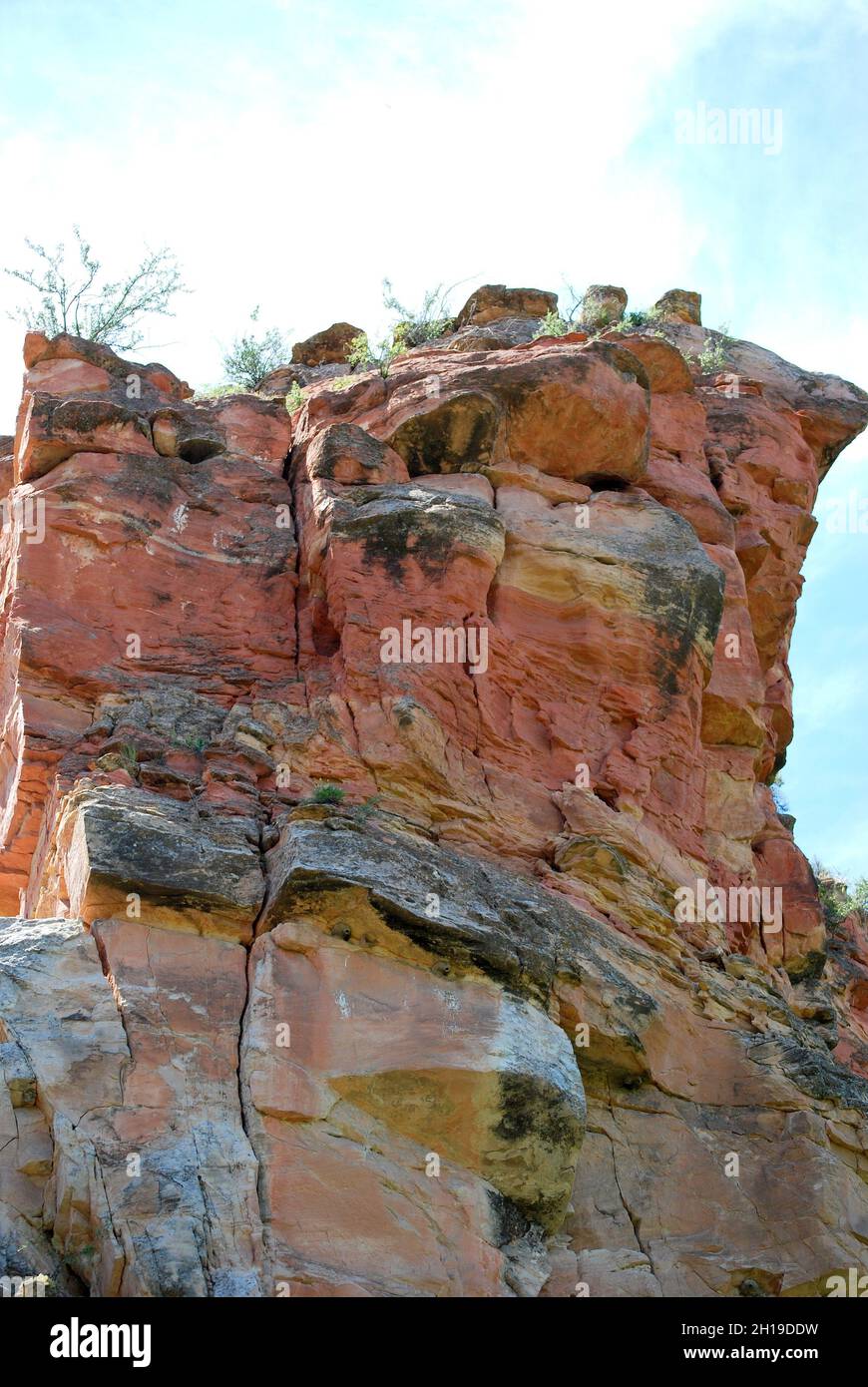 A low angle of a rocky cliff gleaming under the cloudy blue sky in the ...
