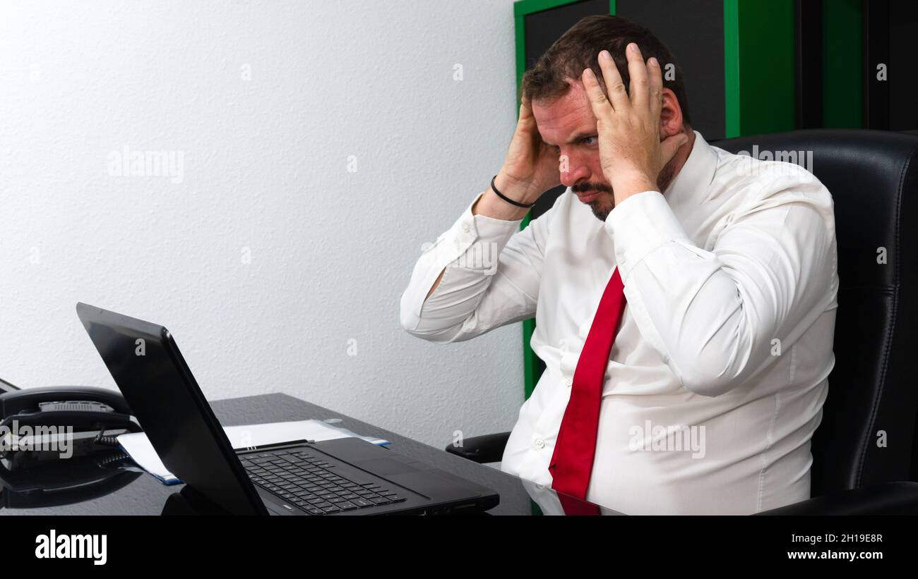 A mad, angry caucasian man sitting at the office and working with his ...