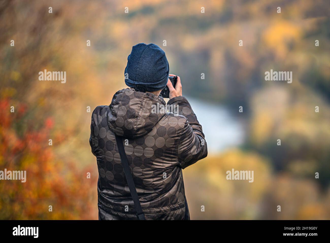 back view of Young photographer takes pictures of autumn landscape ...