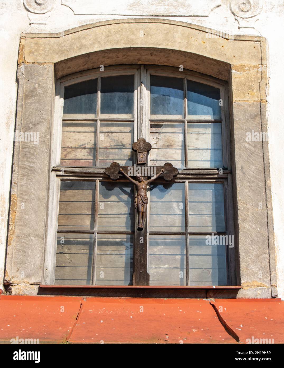 Cross with the crucified Jesus on the window of a baroque chapel from ...