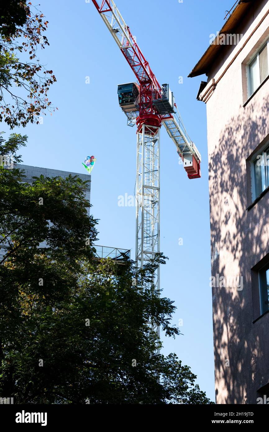 A vertical shot of a high lifting device and trees under a clear blue ...