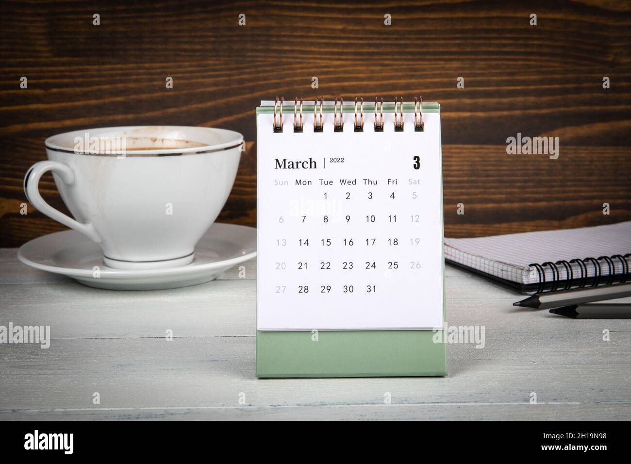 March 2022. Desk calendar, coffee mug and office supplies on the desk ...