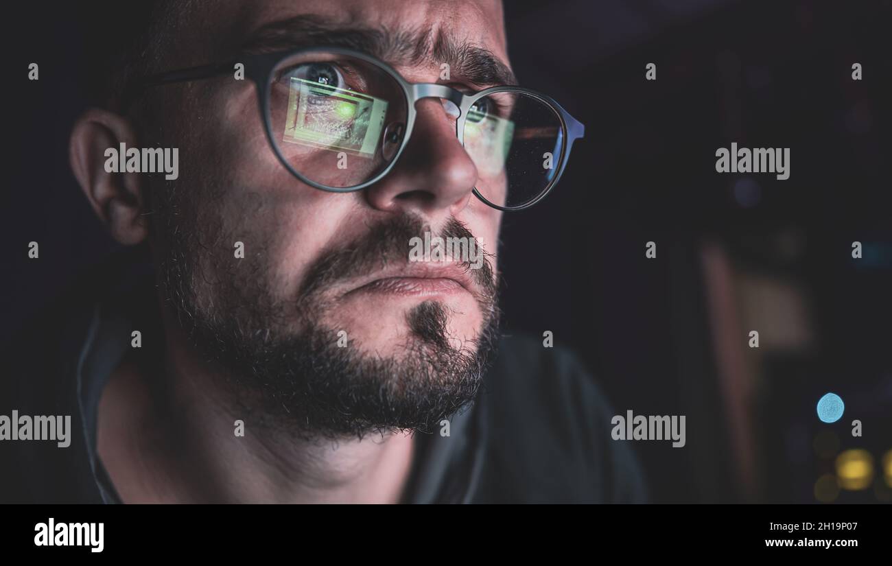 A man stares intently at a computer screen in the dark at night Stock ...