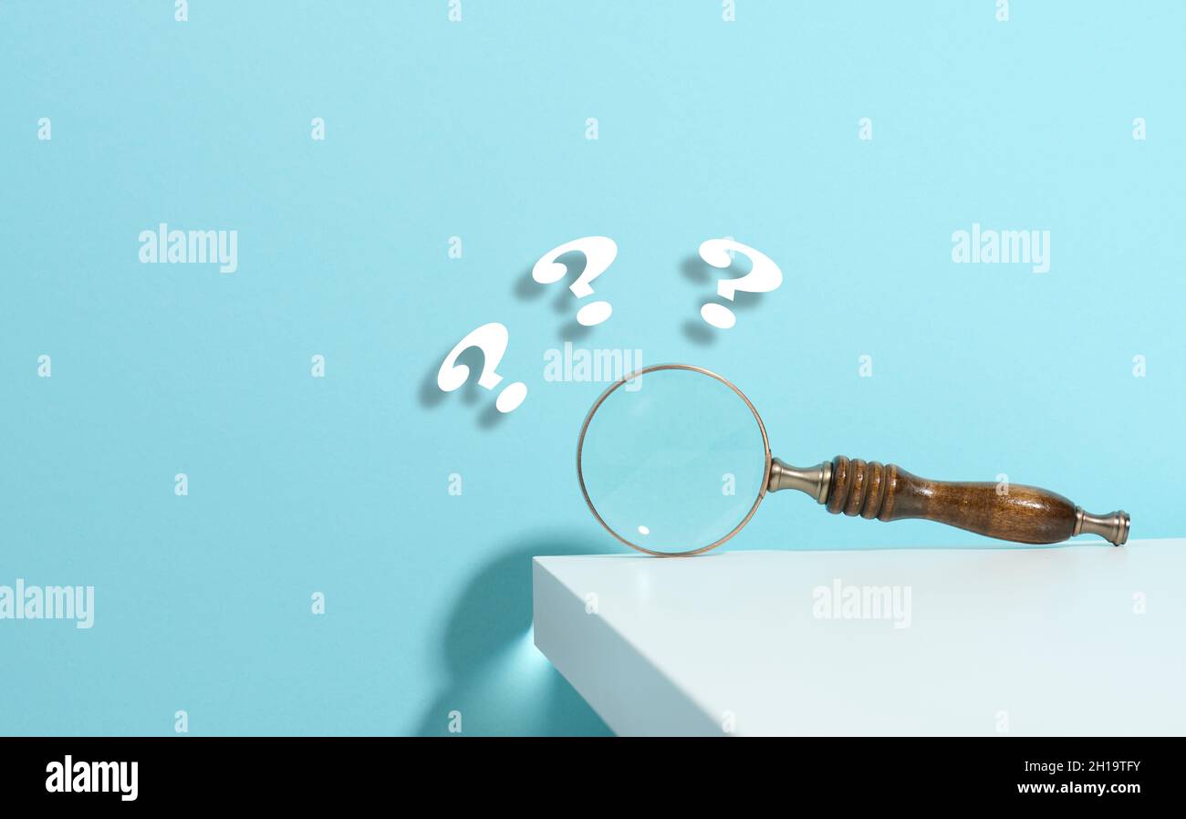wooden magnifying glass and question marks on a blue background. The ...
