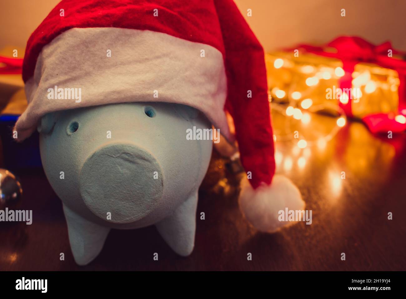 Piggy bank with Santa Claus hat on blurred christmas background with ...