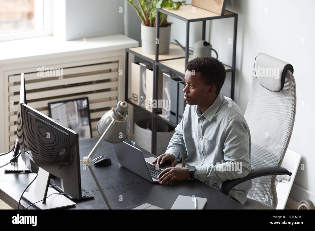 High angle portrait of focused African-American man using computer with ...