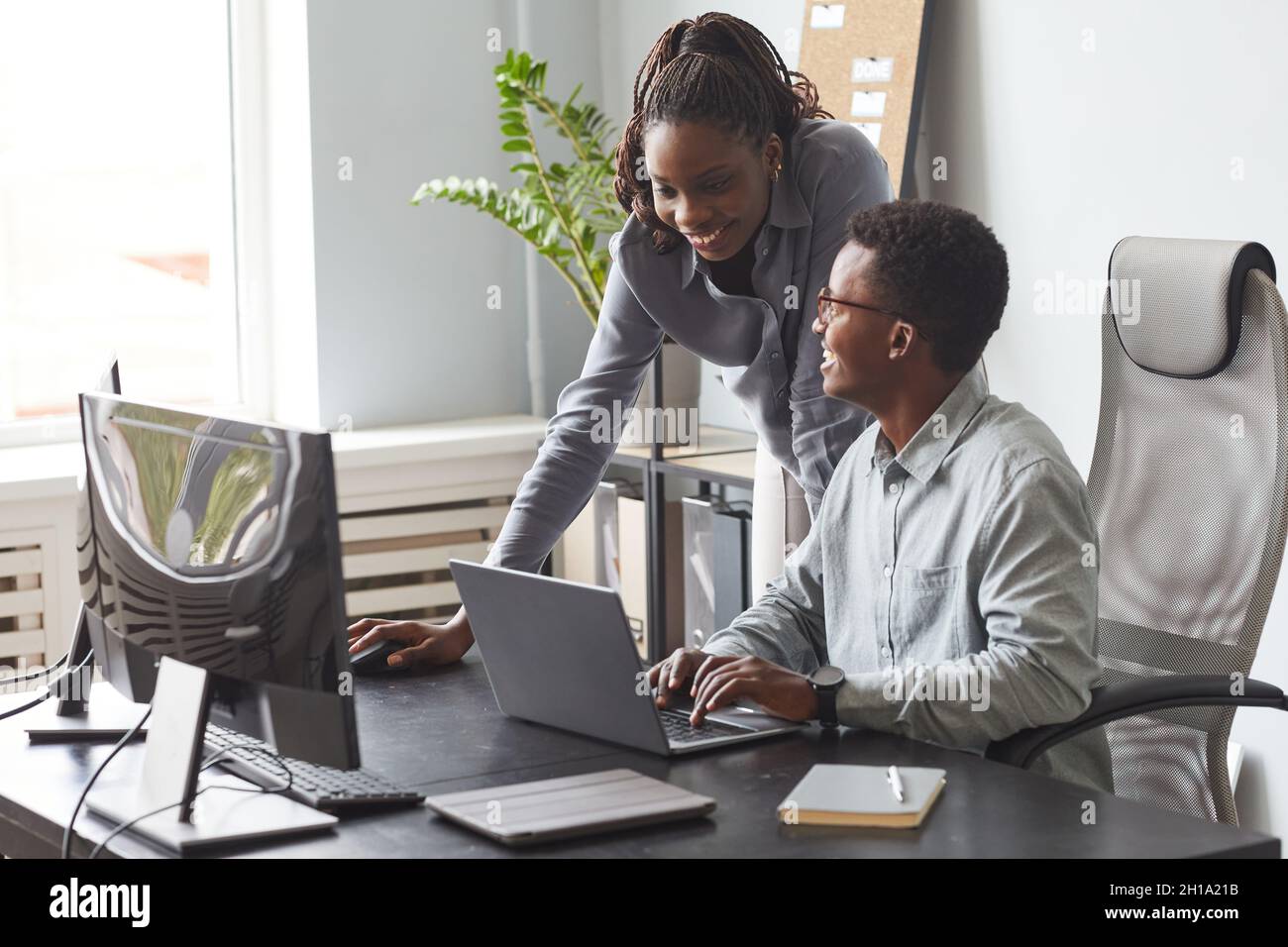 Portrait of two young people looking at computer screen and smiling ...