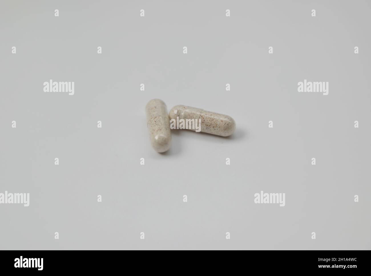 A couple of transparent cylindrical pill capsules with green powder ...