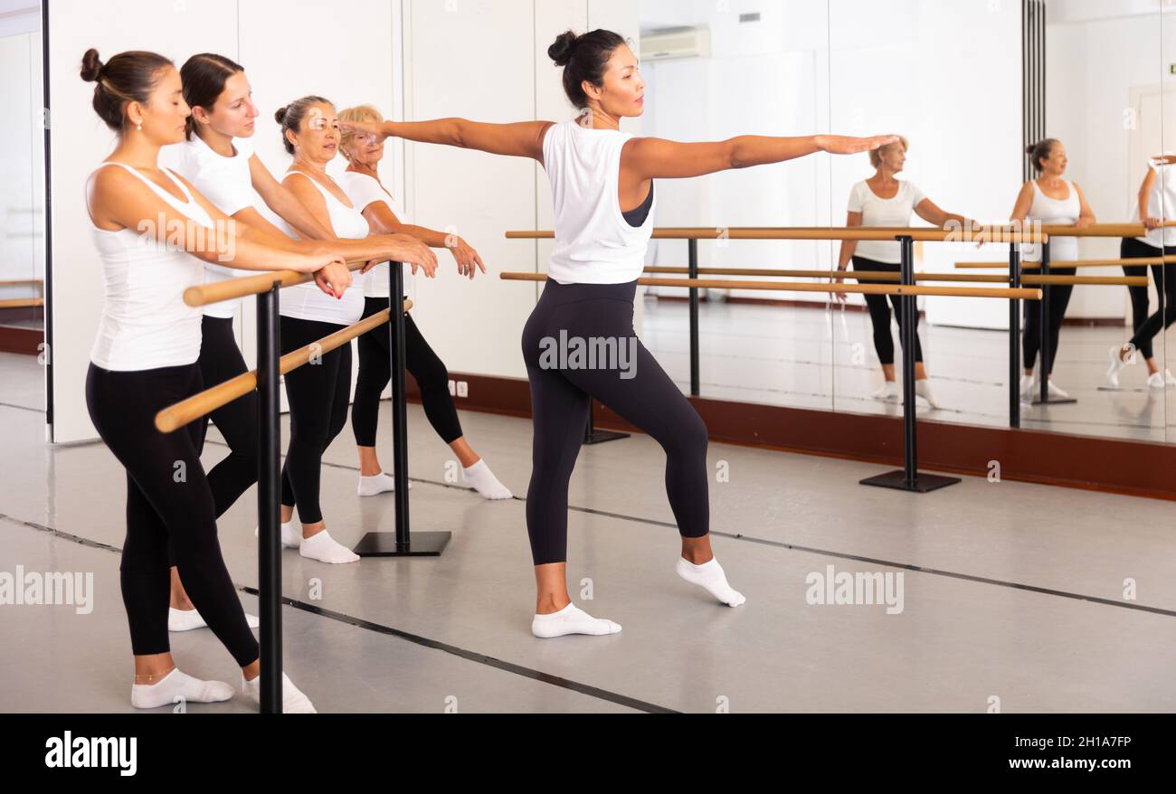 Female ballet teacher showing dancers how to dance ballet in studio ...