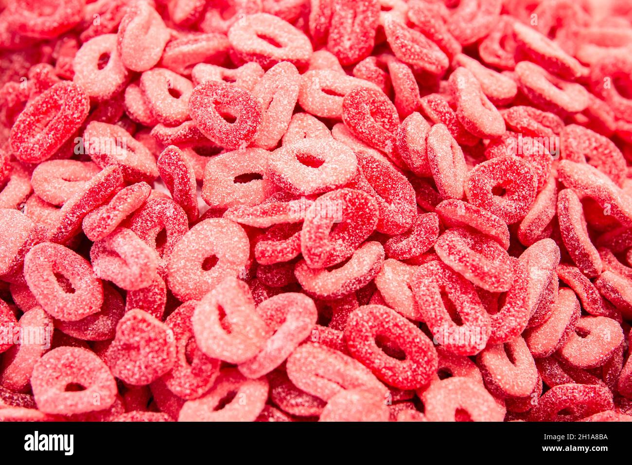 Bright red background with curly gummy gummy sweets Stock Photo - Alamy