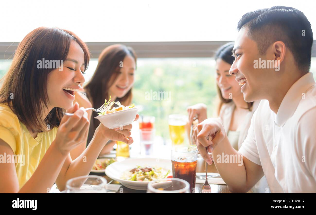 Happy Young group enjoying food and drink in restaurant Stock Photo - Alamy