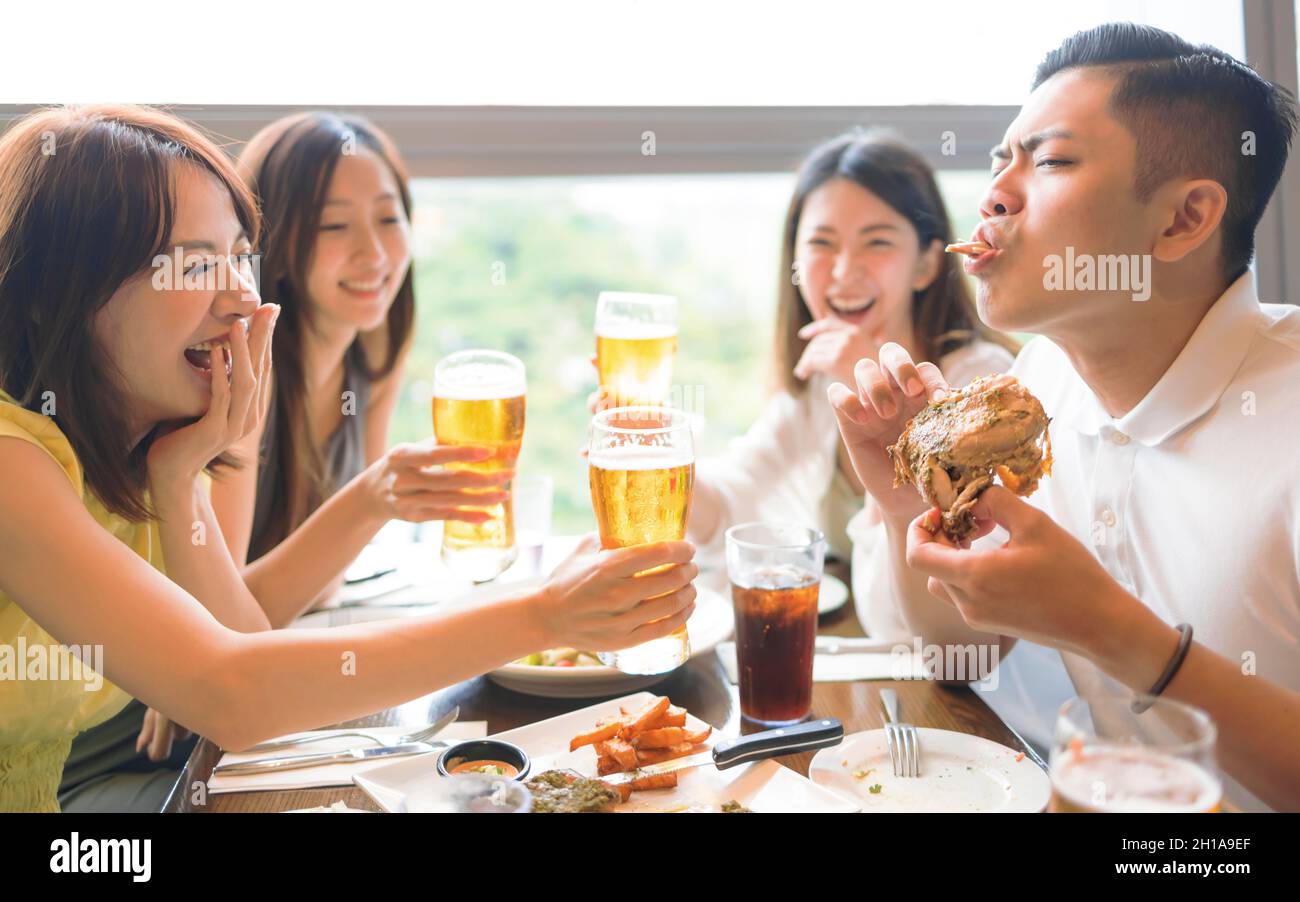 Happy Young group enjoying food and drink in restaurant Stock Photo - Alamy