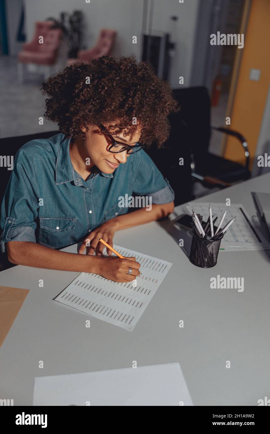 Young multiethnic lady making notes on document Stock Photo - Alamy
