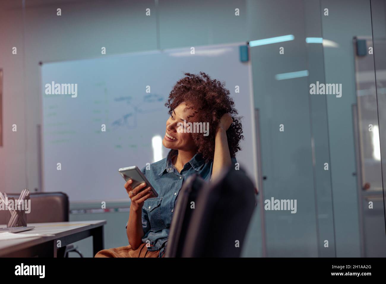 Smiling young lady using mobile phone in the office Stock Photo - Alamy