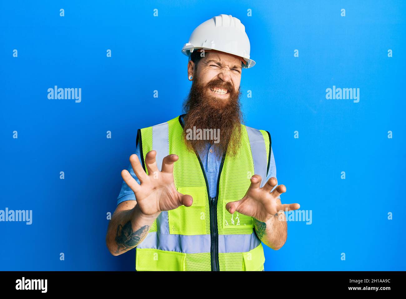 Redhead man with long beard wearing safety helmet and reflective jacket ...