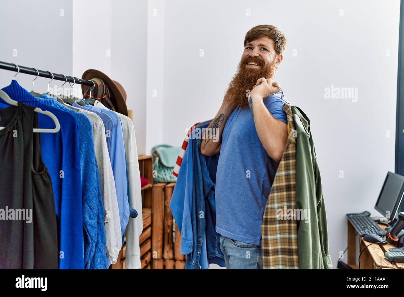 Young redhead customer man smiling happy holding hanger with clothes at ...