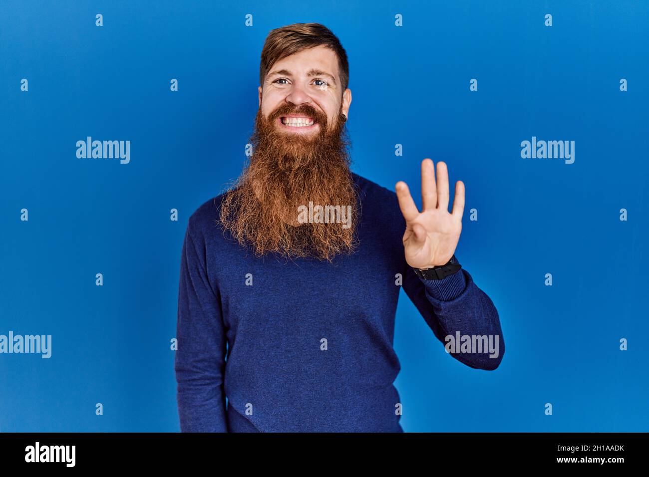 Redhead man with long beard wearing casual blue sweater over blue ...