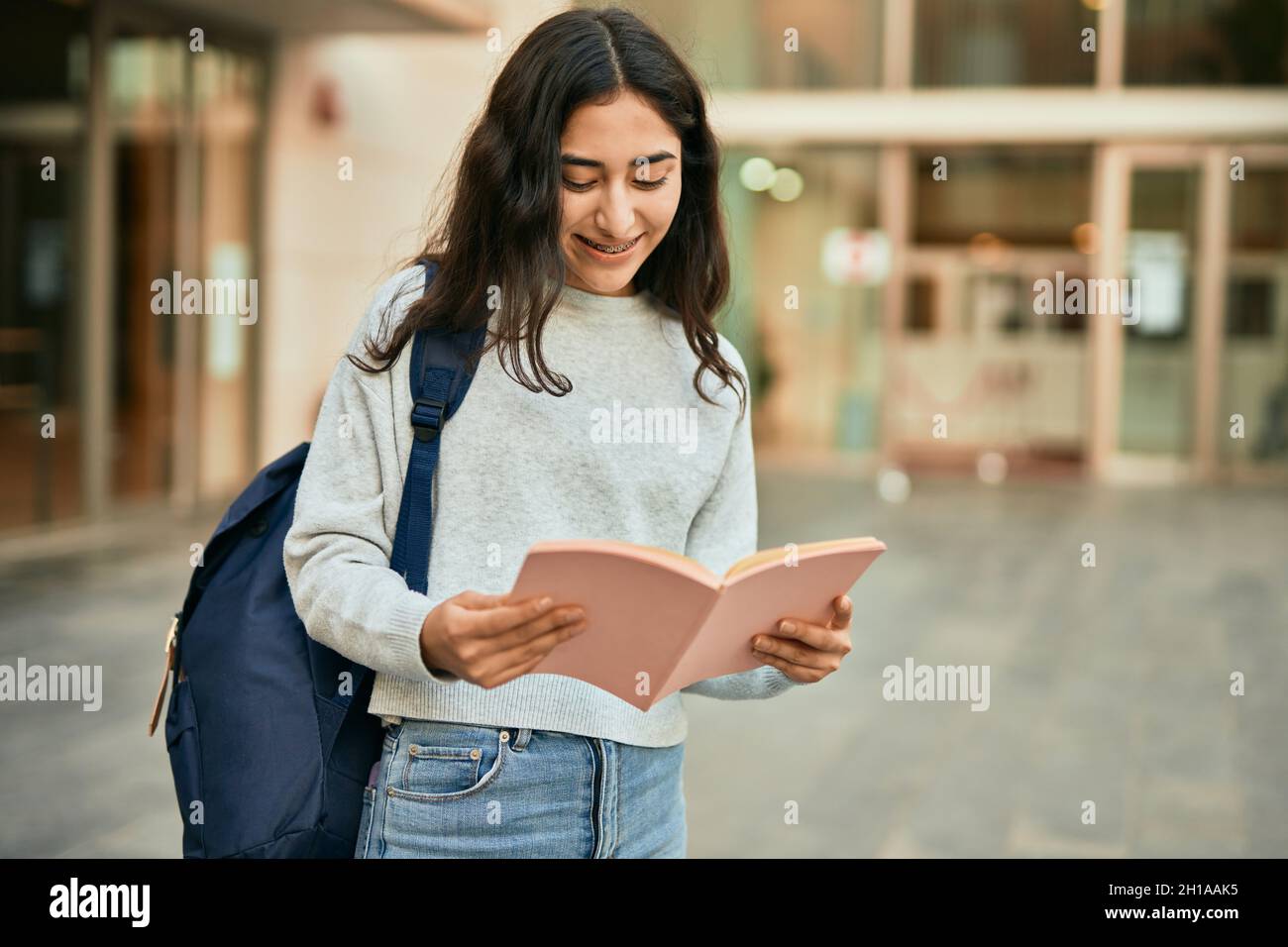 Young middle east student girl smiling happy reading book at the city ...