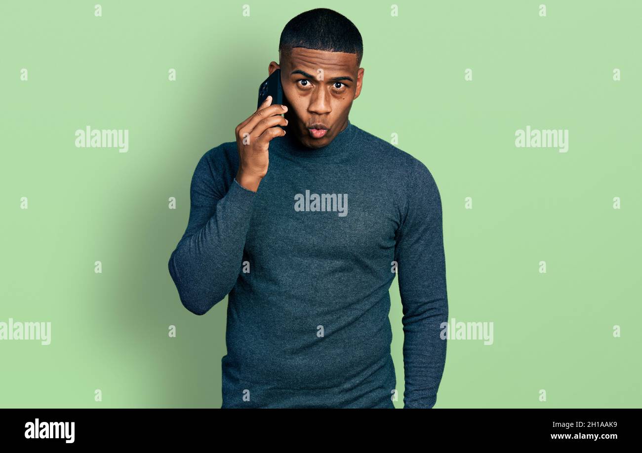 Young black man having conversation talking on the smartphone scared ...