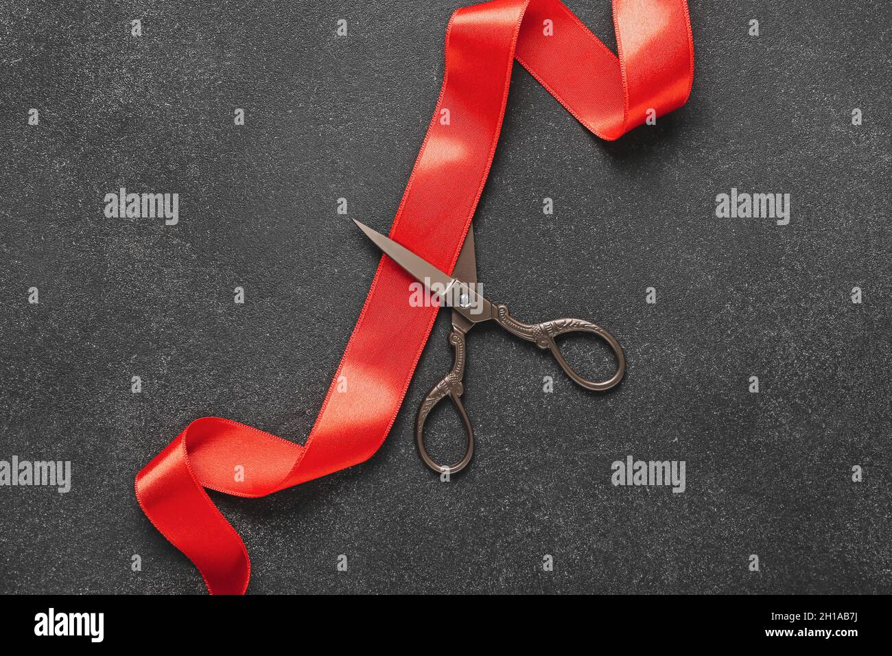Shiny red ribbon and scissors on dark background Stock Photo - Alamy