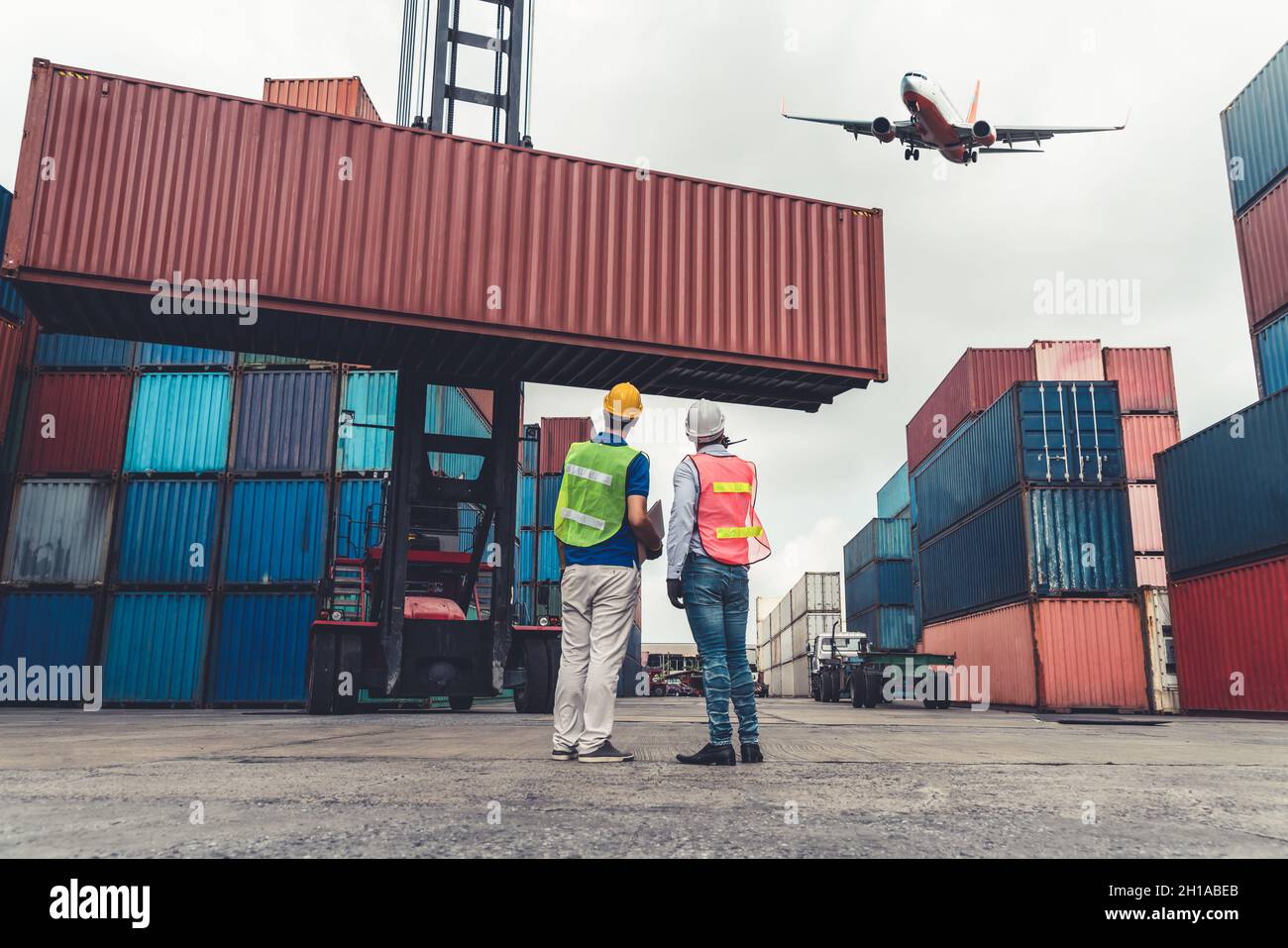 Industrial worker works with co-worker at overseas shipping container ...