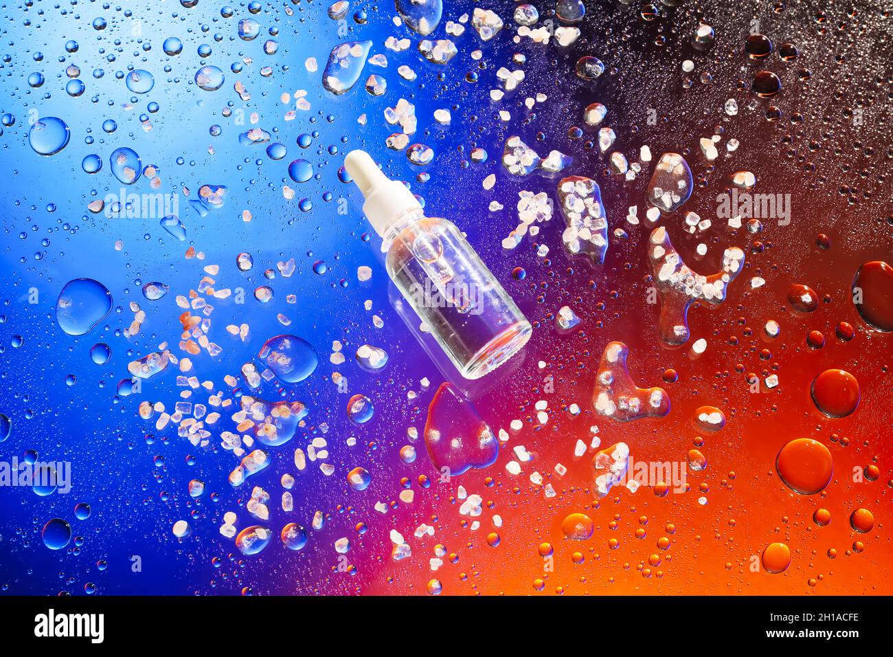 Bottle of cosmetic product and sea salt on color background with water ...