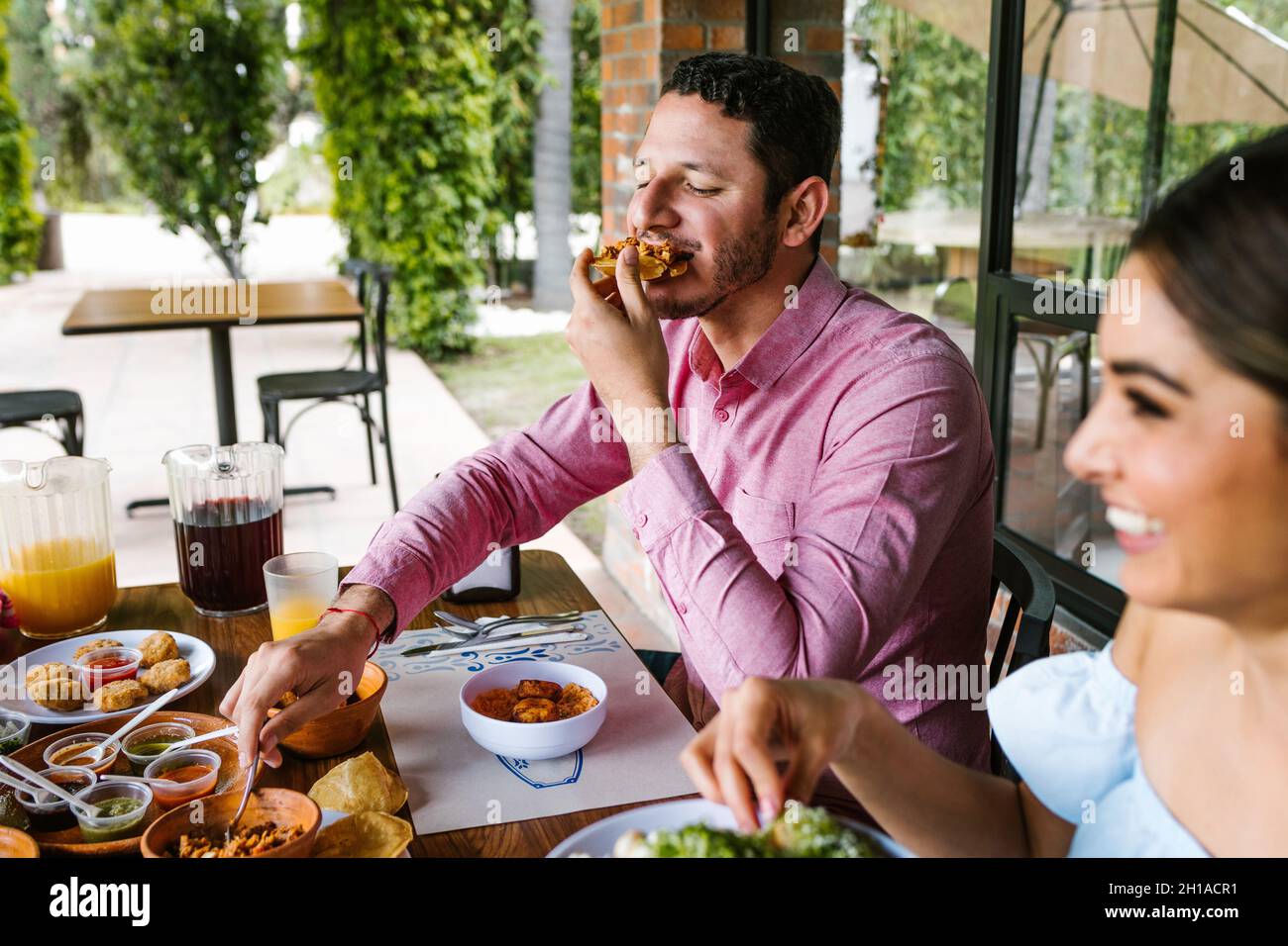 young latin man eating mexican tacos on a restaurant terrace in Mexico ...